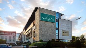 Um edifício moderno com a placa 'Carlton' e a placa 'Mayfly Restaurant'.