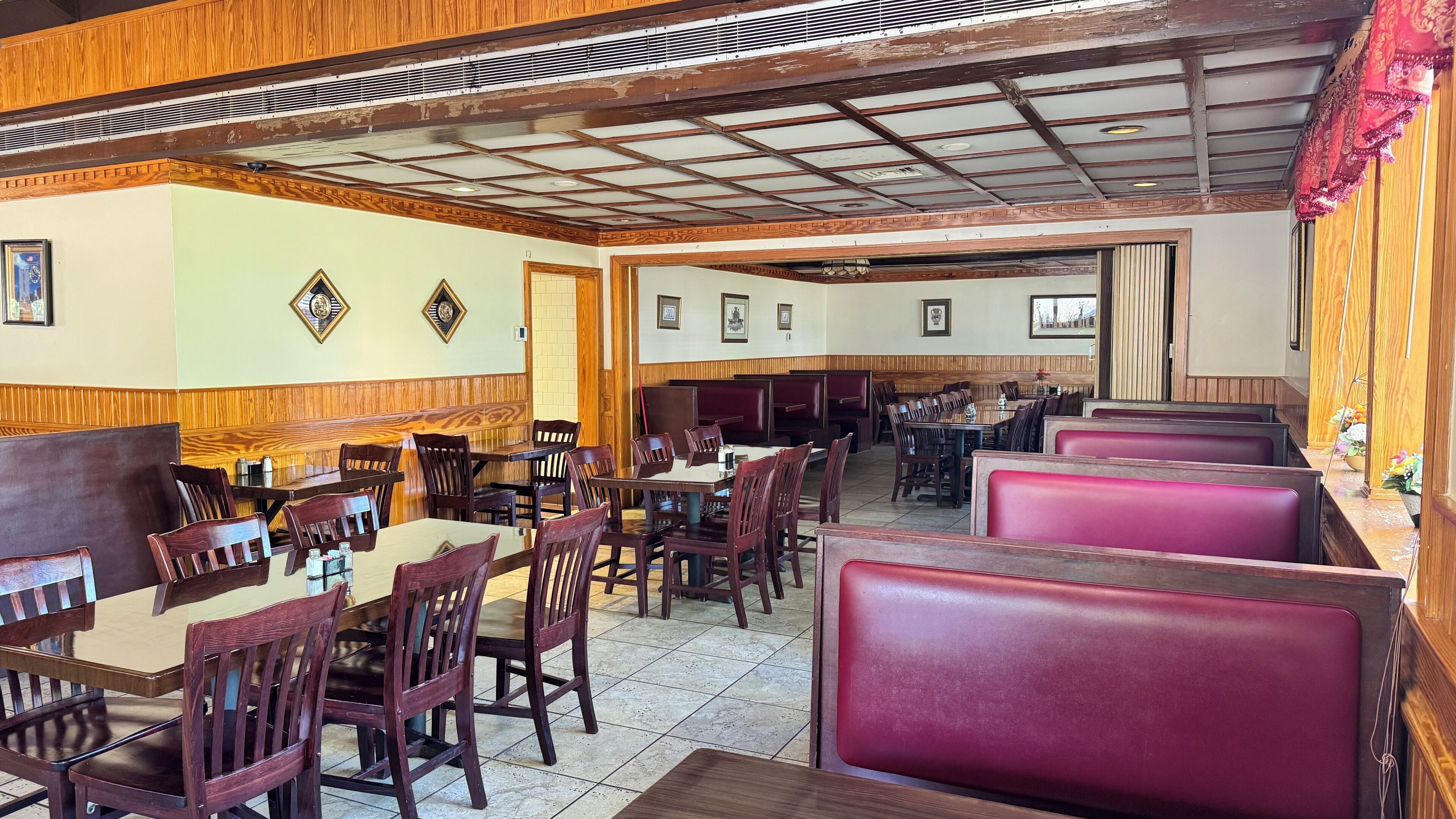 Um restaurante com cabines e mesas, painéis de madeira e quadros nas paredes.