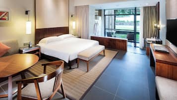 Quarto de hotel com uma cama grande, uma mesa de escritório, uma cadeira, televisão e varanda com vista para o exterior.
