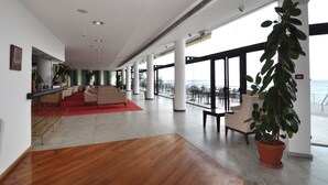 Um hall amplo com carpete vermelho, piso de madeira e uma grande planta em vaso.