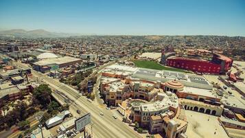 Vista aérea de um horizonte urbano com um estádio em destaque, ruas largas e edifícios ao redor.