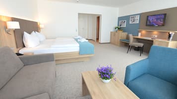 Quarto de hotel com cama, escrivaninha, cadeira e sofá.