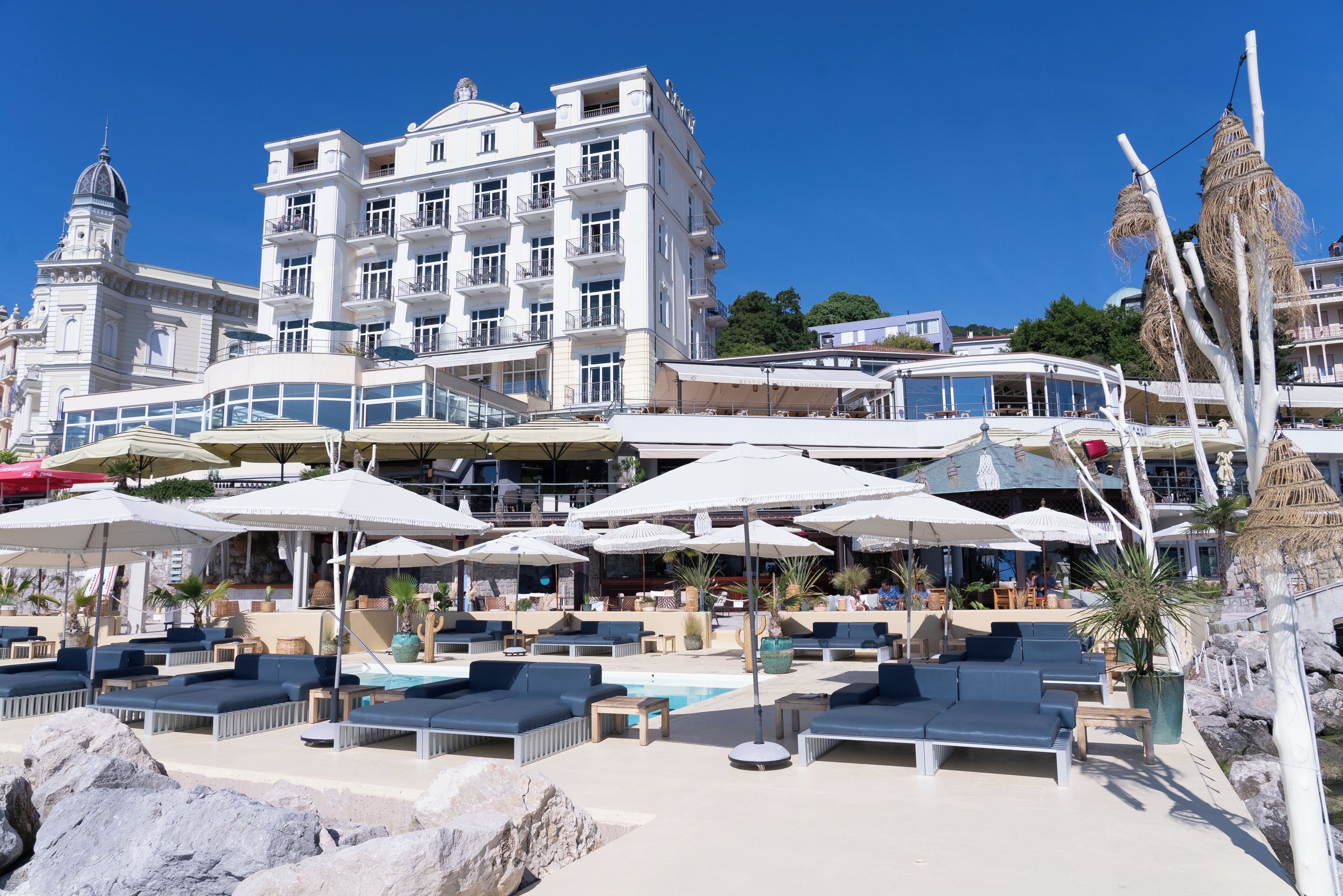 Resort com várias piscinas, áreas de descanso com guarda-sóis e um prédio grande com sacadas.