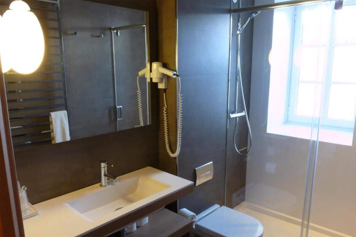 Um banheiro moderno com um espelho grande, pia, vaso sanitário e área de chuveiro.