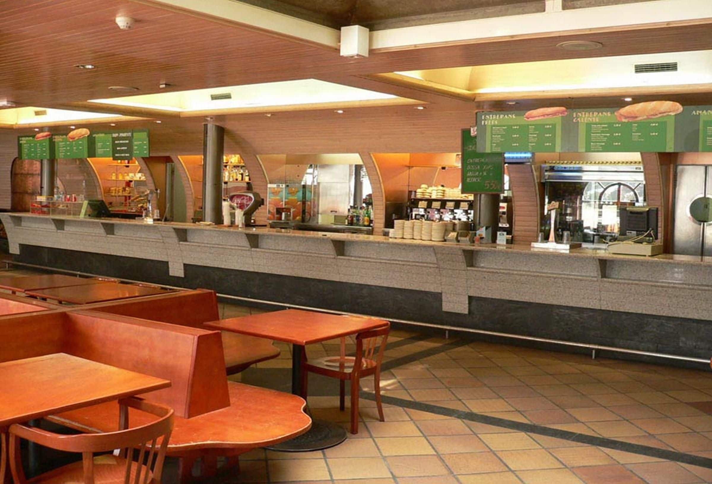 Uma cafeteria com balcão, área de estar e cardápio.