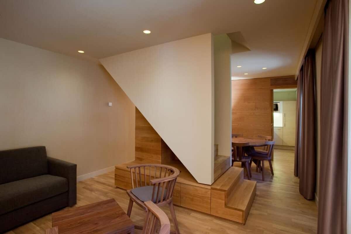 Uma sala de estar moderna com escada de madeira, área de jantar e sofá.