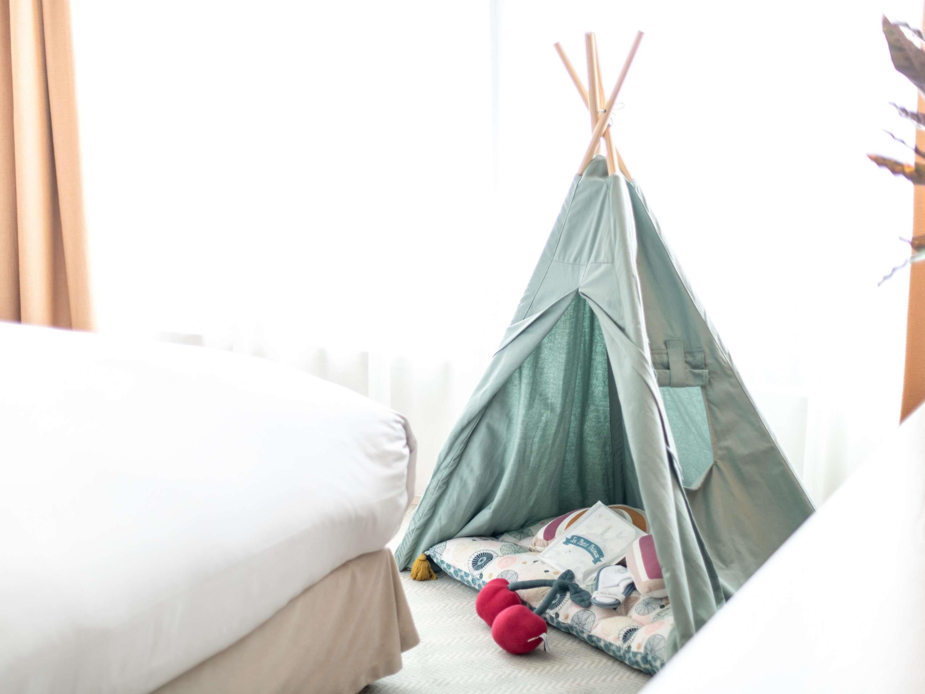 Quarto de criança com uma cama, uma tenda verde e um brinquedo.