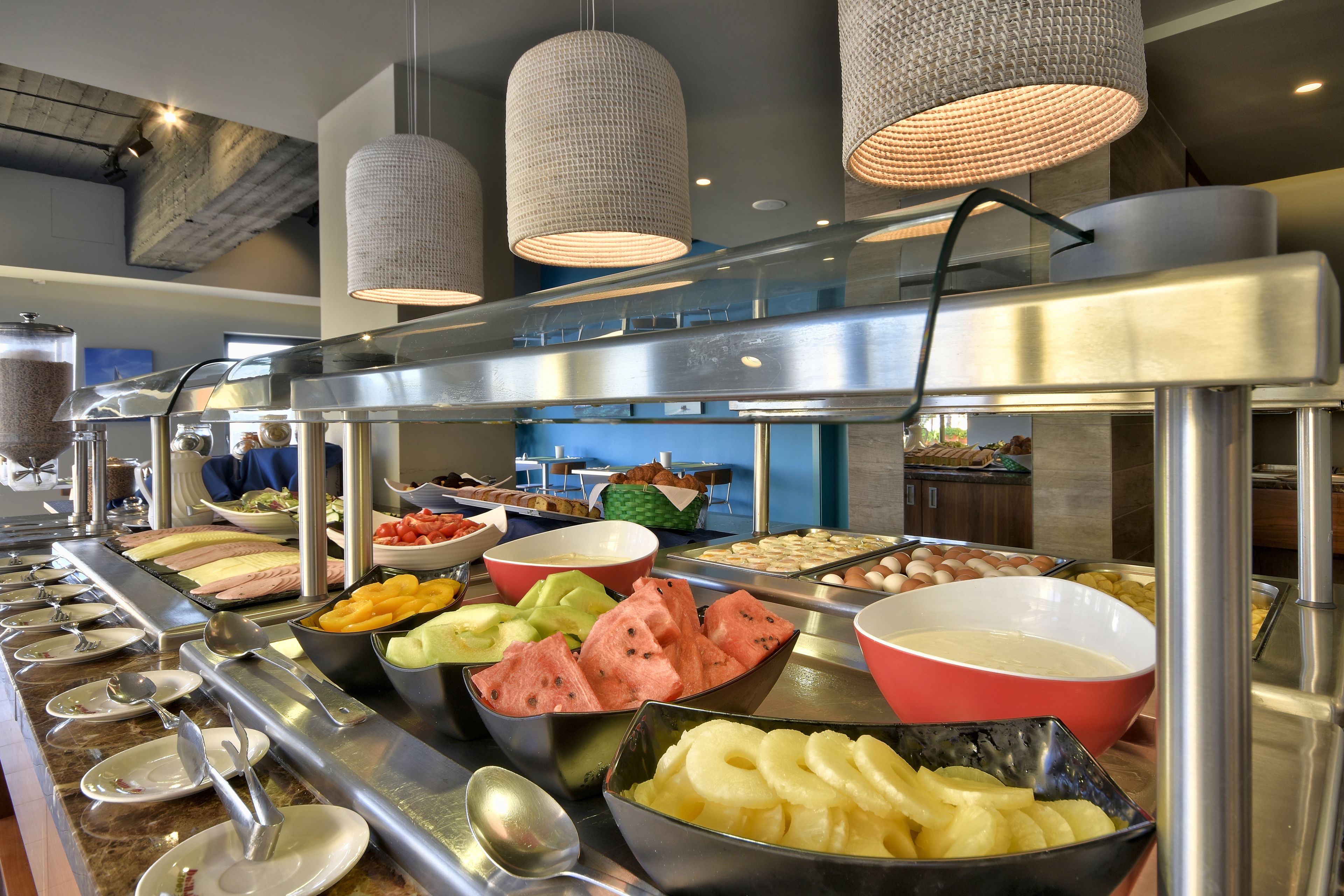 Buffet com diversos alimentos e utensílios de servir.