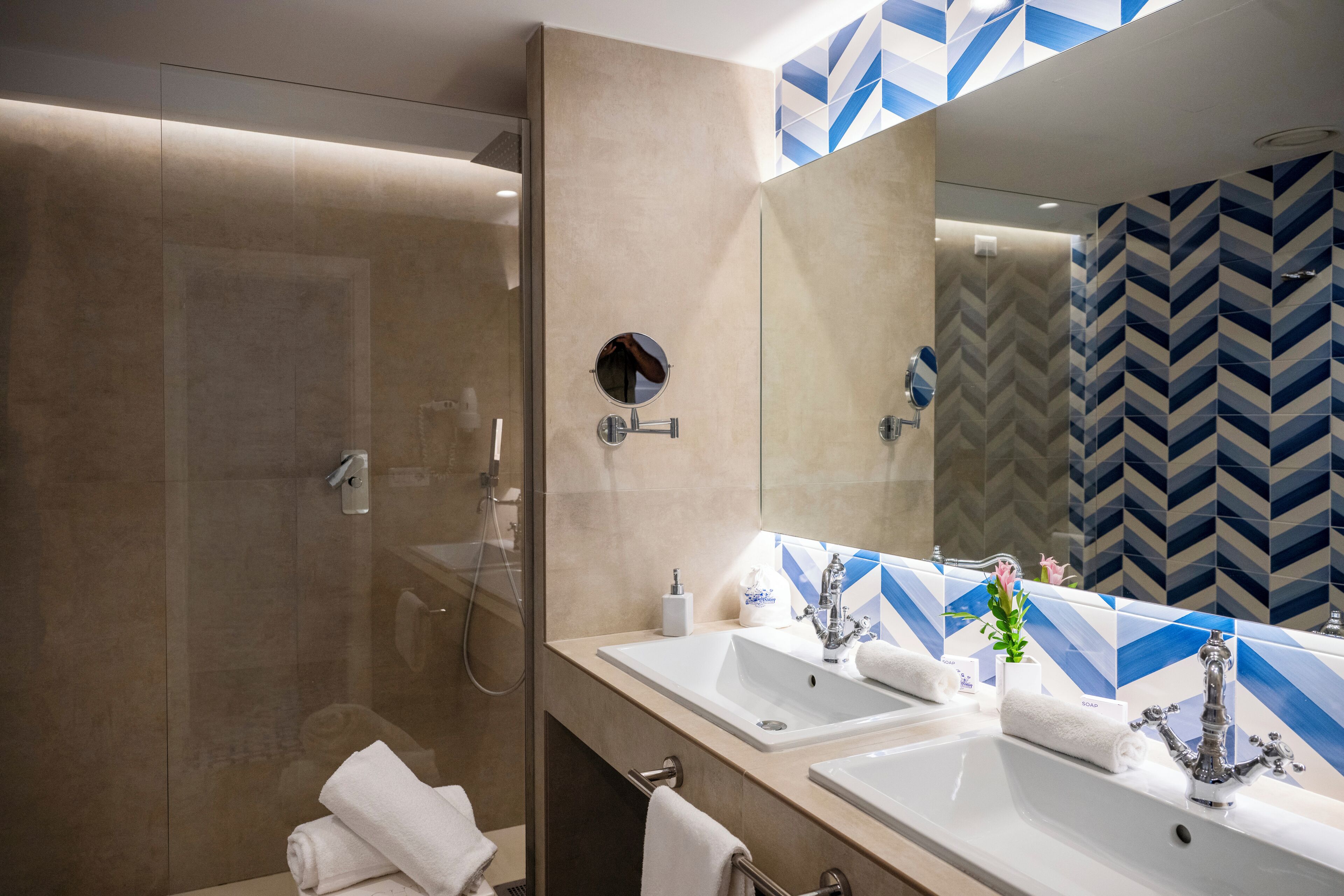 Uma casa de banho moderna com duas pias, um espelho grande e zona de duche.