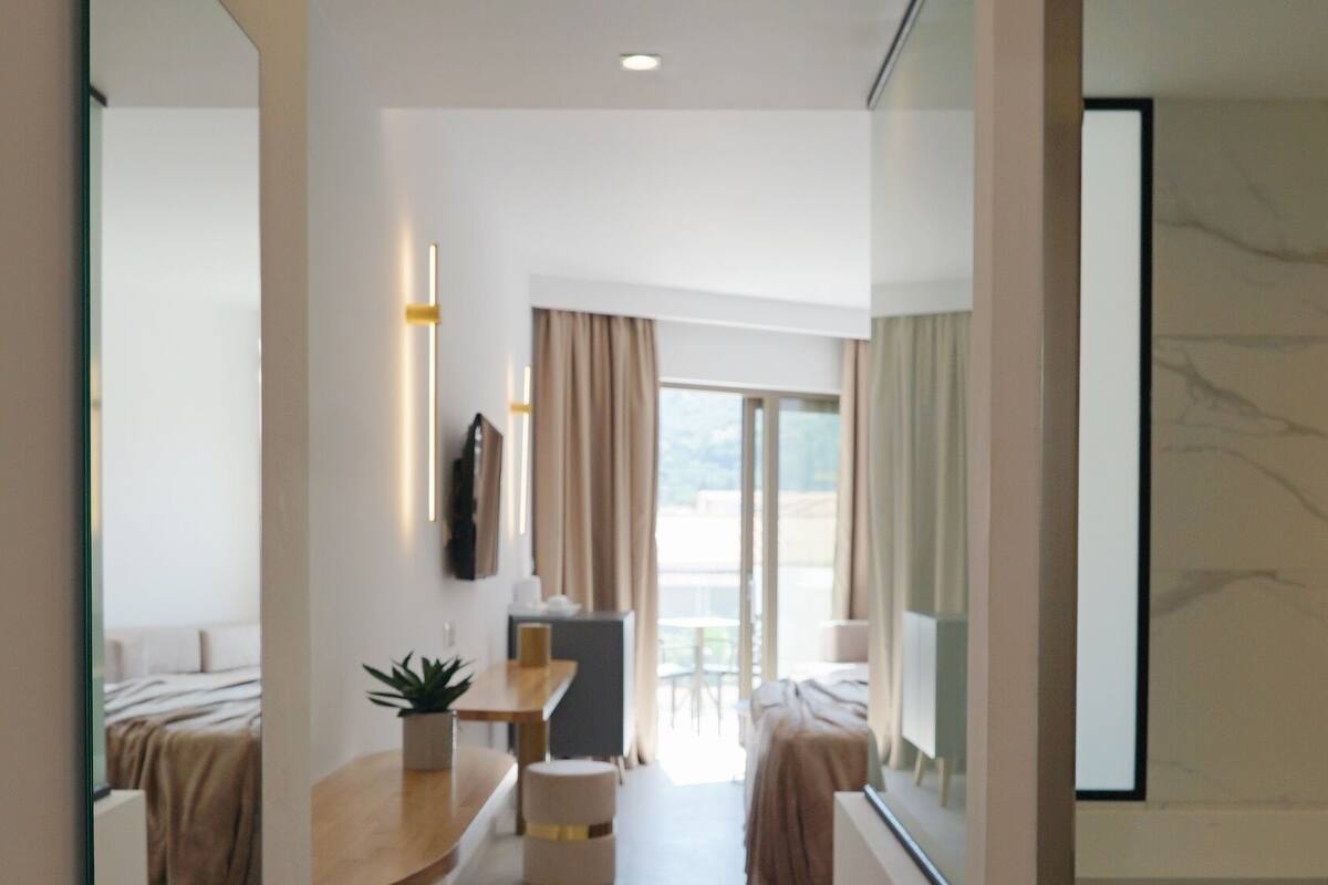 Corredor moderno de hotel com área de refeições, uma cama e uma grande janela.