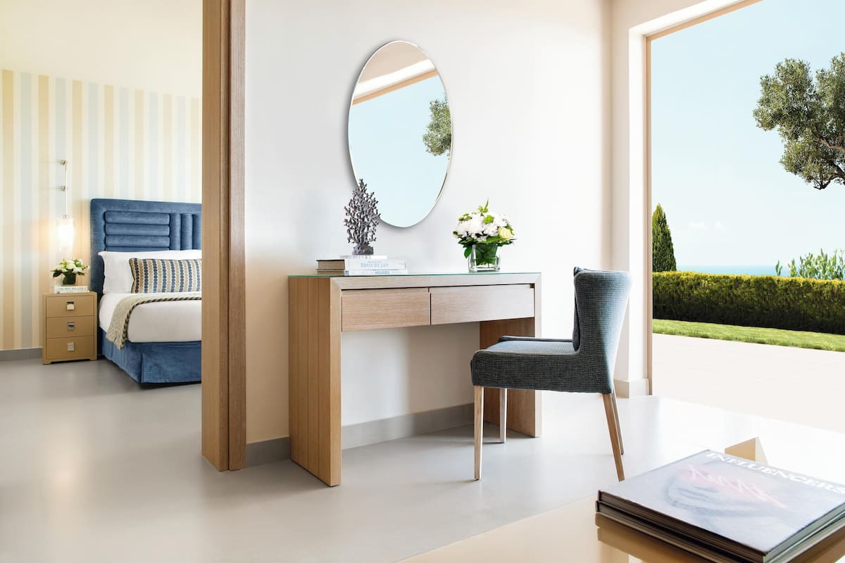 Quarto moderno com uma cama, escrivaninha, cadeira e um espelho grande.
