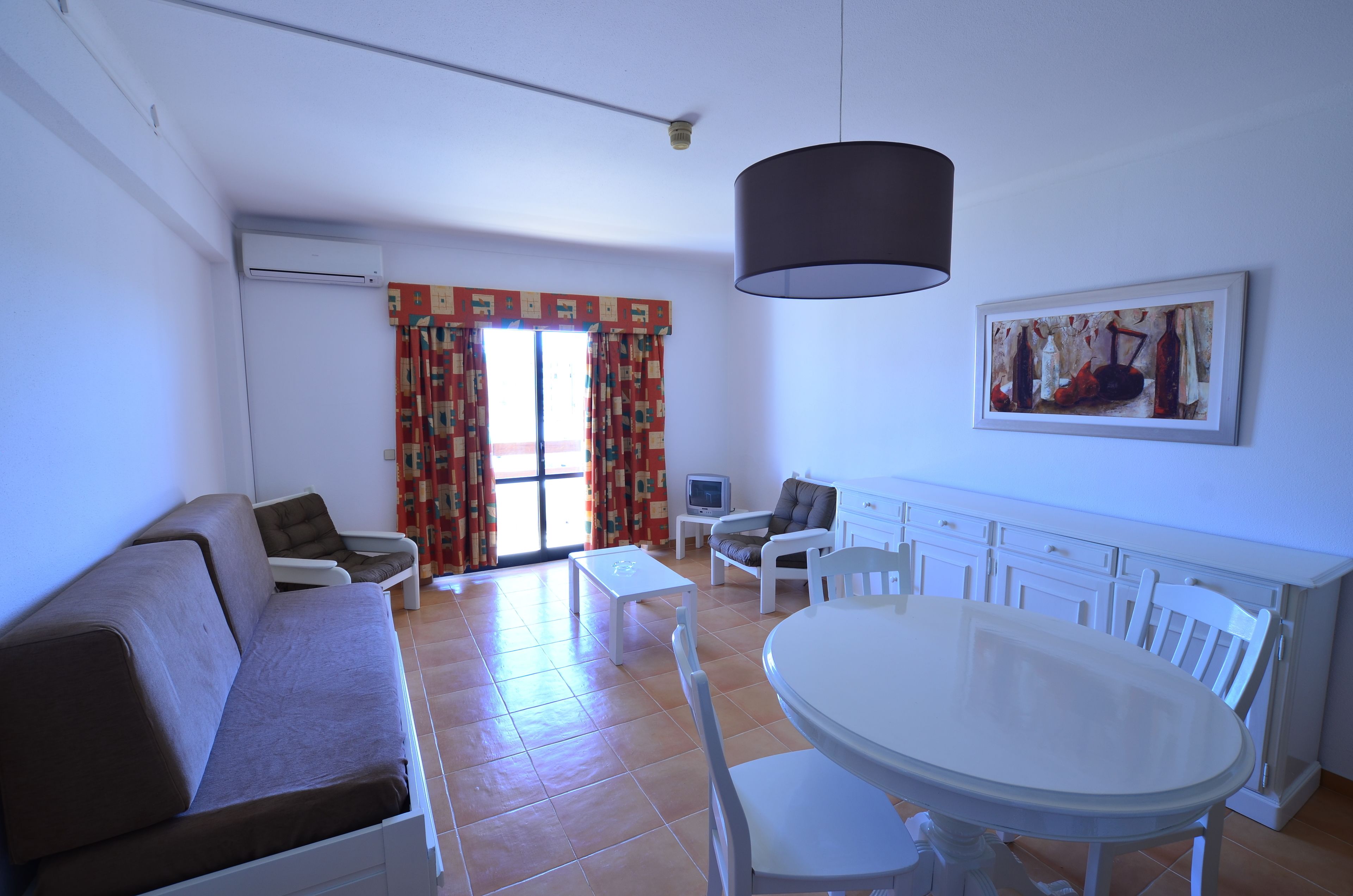 Uma sala de estar com sofá, mesa de jantar e televisão.