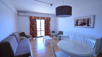 Uma sala de estar com sofá, mesa de jantar e televisão.