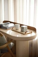 Uma mesa de madeira com um livro, uma xícara e uma caixa sobre um suporte.