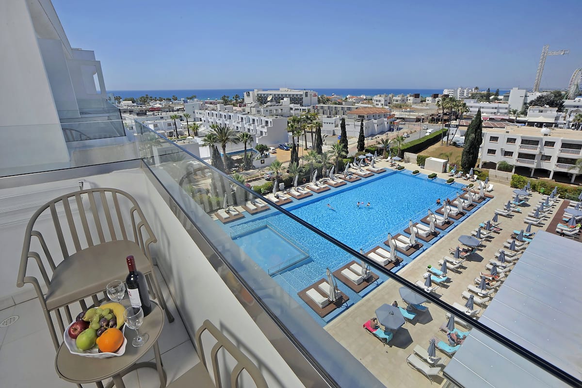 Piscina no terraço com espreguiçadeiras e uma mesa com frutas e vinho.