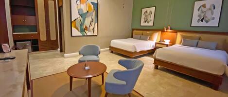 Quarto de hotel com duas camas, uma escrivaninha, uma cadeira e obras de arte nas paredes.