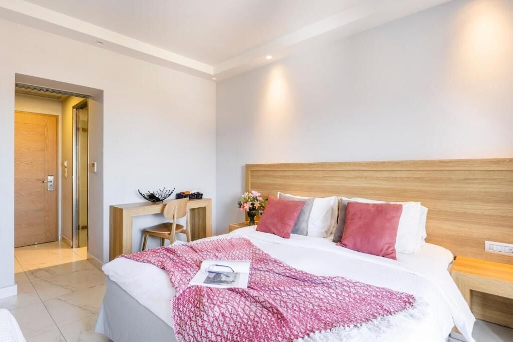 Quarto de hotel moderno com uma cama grande, uma cabeceira de madeira e uma escrivaninha com uma cadeira.