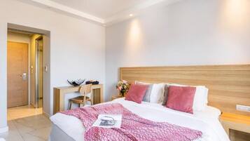 Quarto de hotel moderno com uma cama grande, uma cabeceira de madeira e uma escrivaninha com uma cadeira.