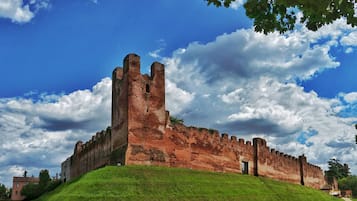 Um castelo histórico com várias torres, localizado numa colina gramada sob um céu parcialmente nublado.