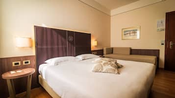 Quarto de hotel com uma cama grande, uma mesa de cabeceira, uma cadeira e uma pequena mesa redonda.