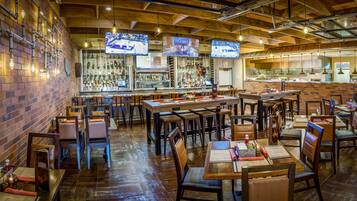 Restaurante com paredes de tijolo, várias televisões e área de bar.