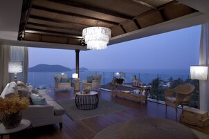 Varanda ampla com vista para o mar, equipada com sofá, cadeiras e mesa de centro.