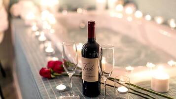 Uma garrafa de vinho sobre uma mesa com dois copos e uma rosa.