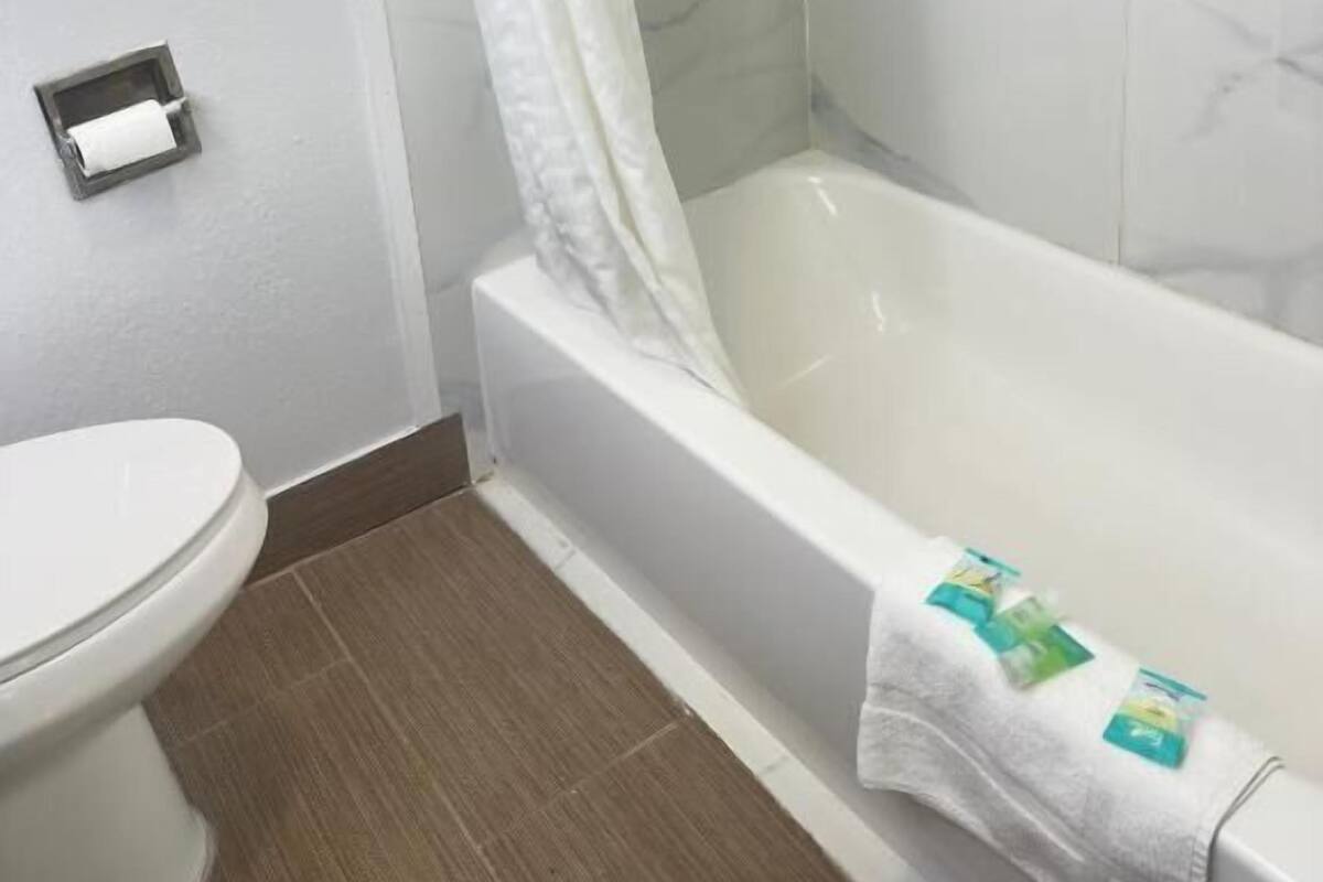 Um banheiro com vaso sanitário, chuveiro com parede de mármore e porta-toalhas com toalha.