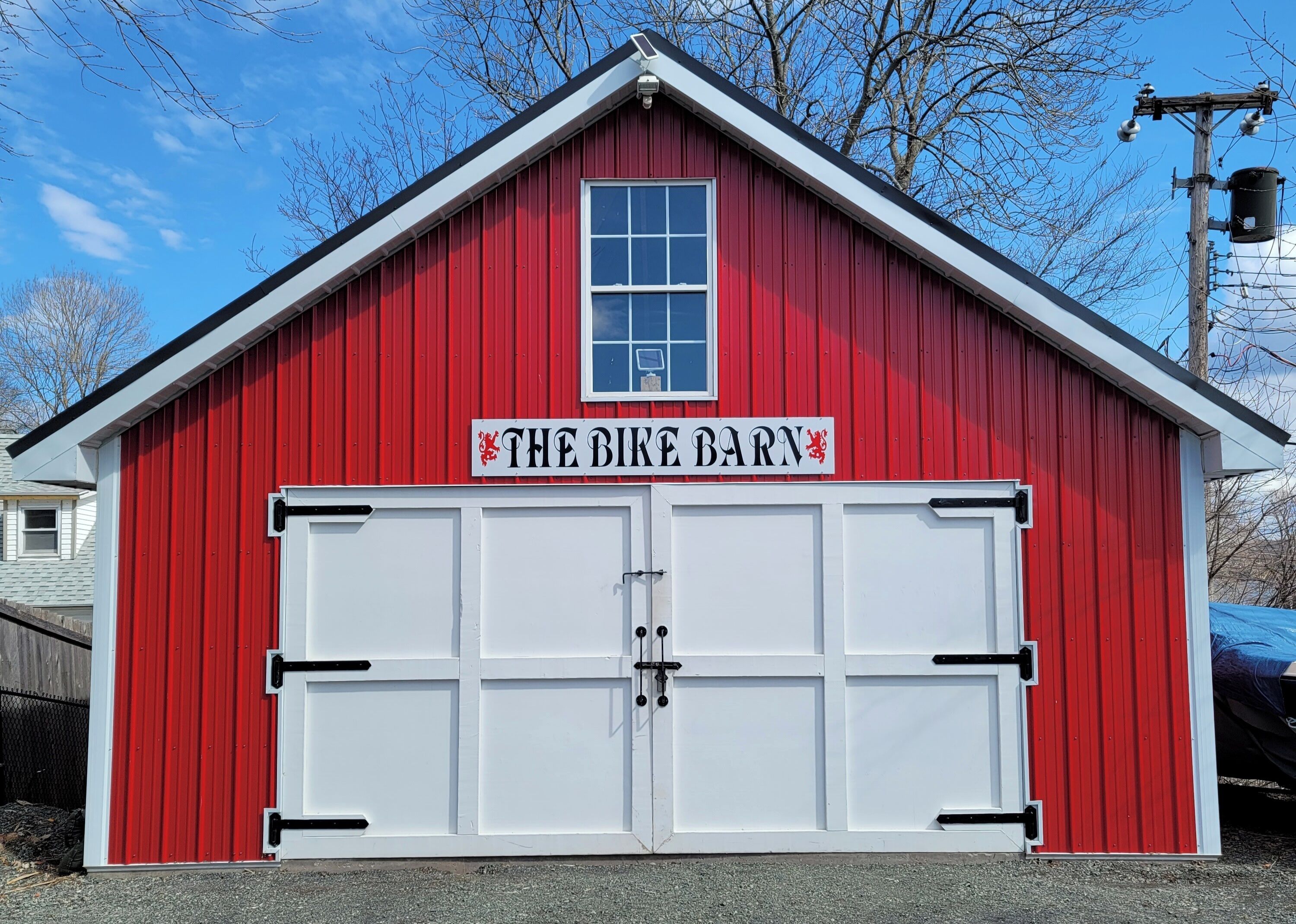 Um edifício vermelho com uma placa que diz "The Bike Barn" e uma porta de garagem branca.