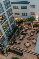Um terraço no telhado com mobiliário para áreas externas, rodeado por vegetação exuberante e arquitetura moderna.