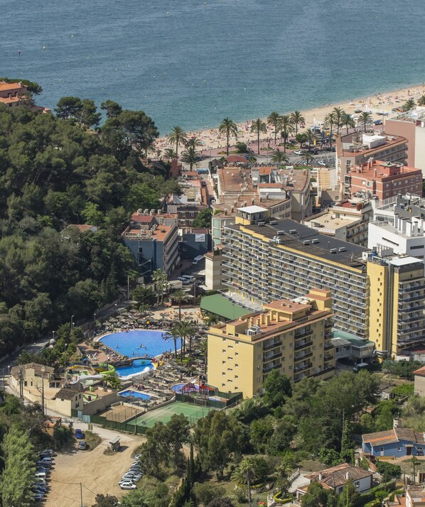 Um resort costeiro com um hotel grande, uma piscina e uma praia.