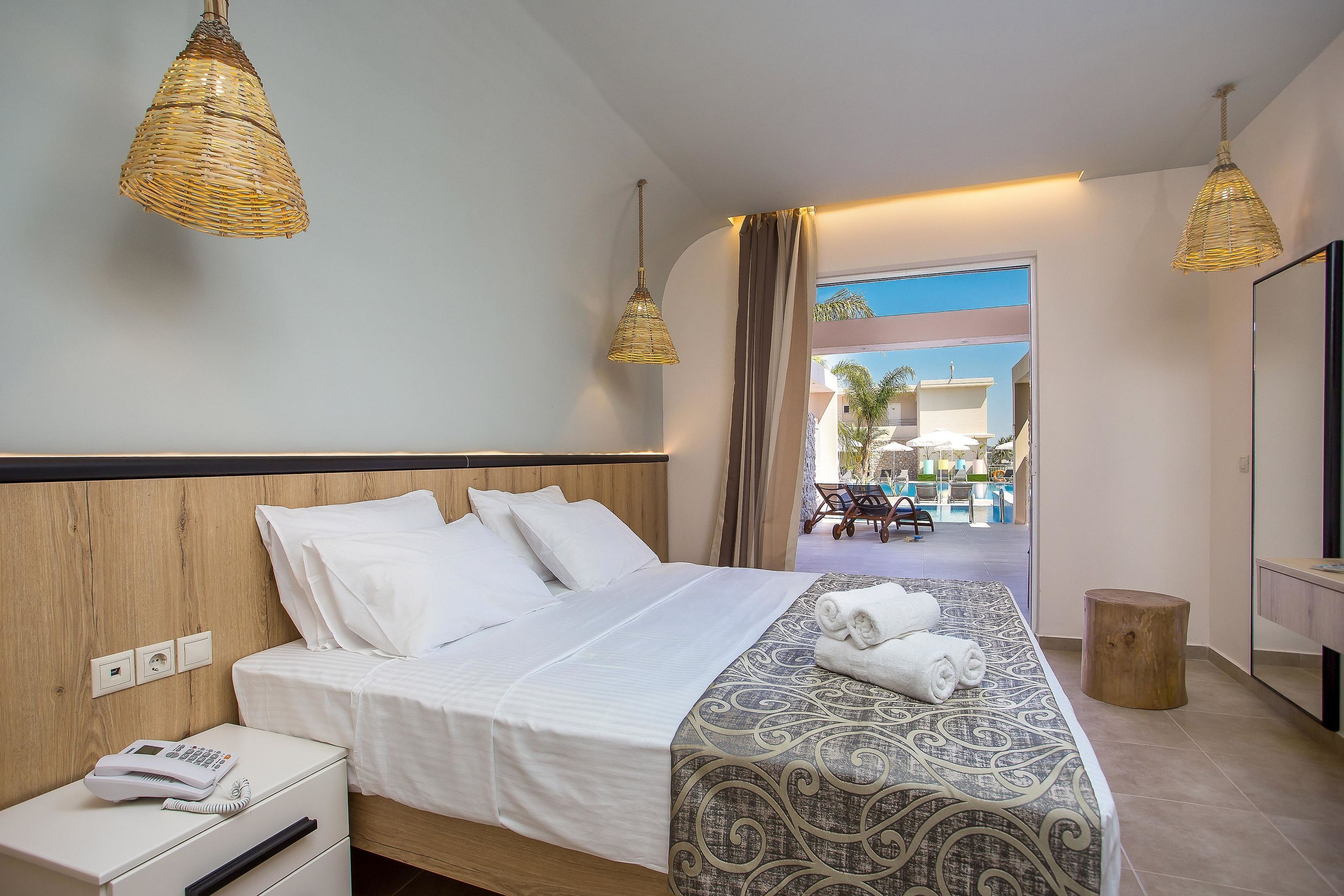 Quarto de hotel com cama, mesa de cabeceira e vista para a área externa.