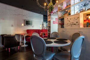 Interior moderno com mesas e cadeiras redondas, um sofá vermelho e iluminação decorativa.