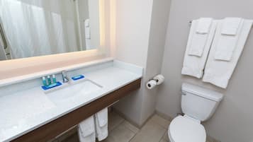 Casa de banho com lavatório branco, espelho e sanita.