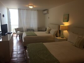 Quarto de hotel com duas camas, televisão, escrivaninha e cadeira.