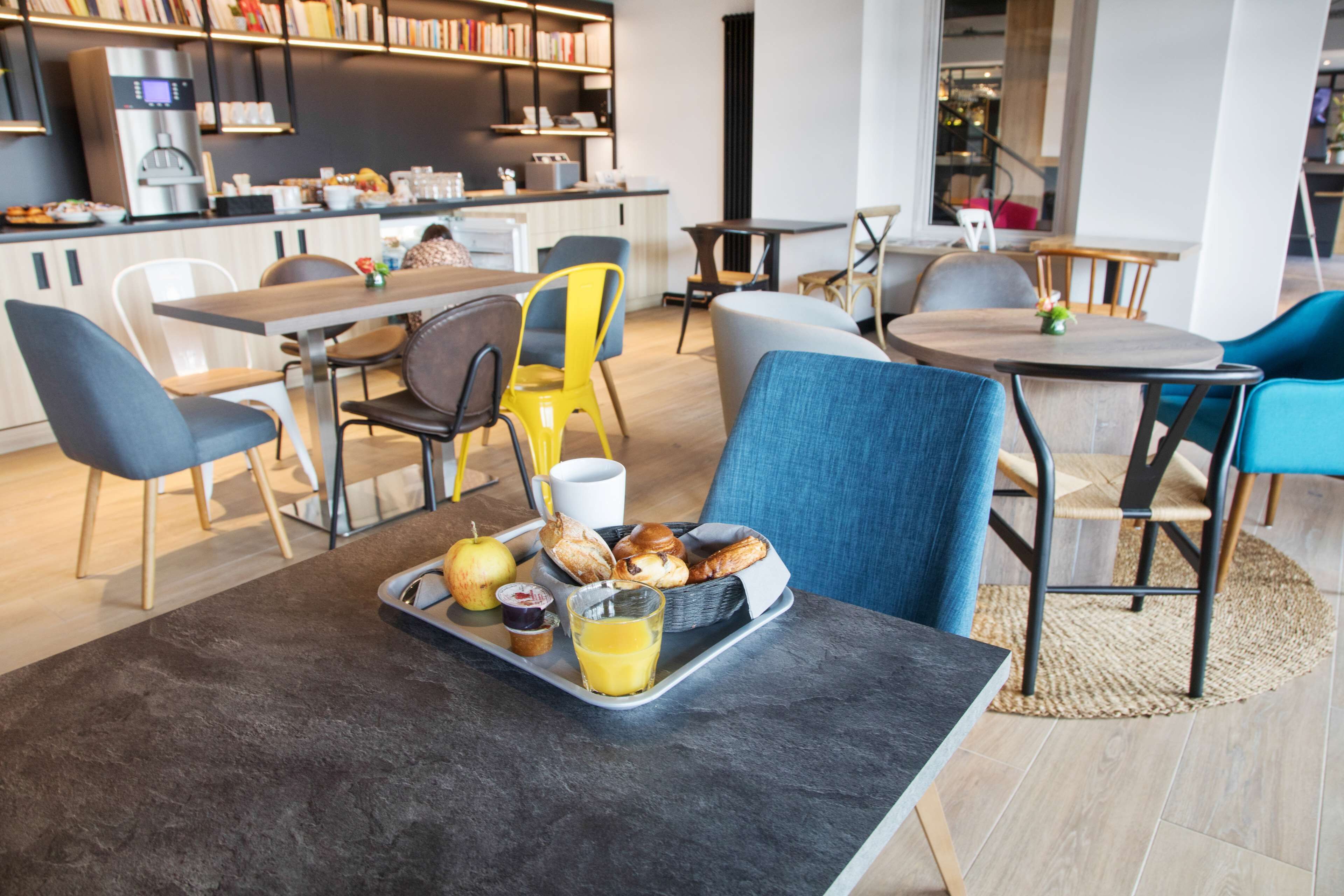 Uma área de refeições moderna, com bandeja de café da manhã, cadeiras e mesas.