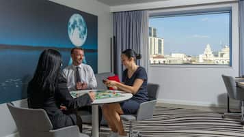 Quarto com vista para a cidade, uma mesa redonda e um quadro grande de lua na parede.