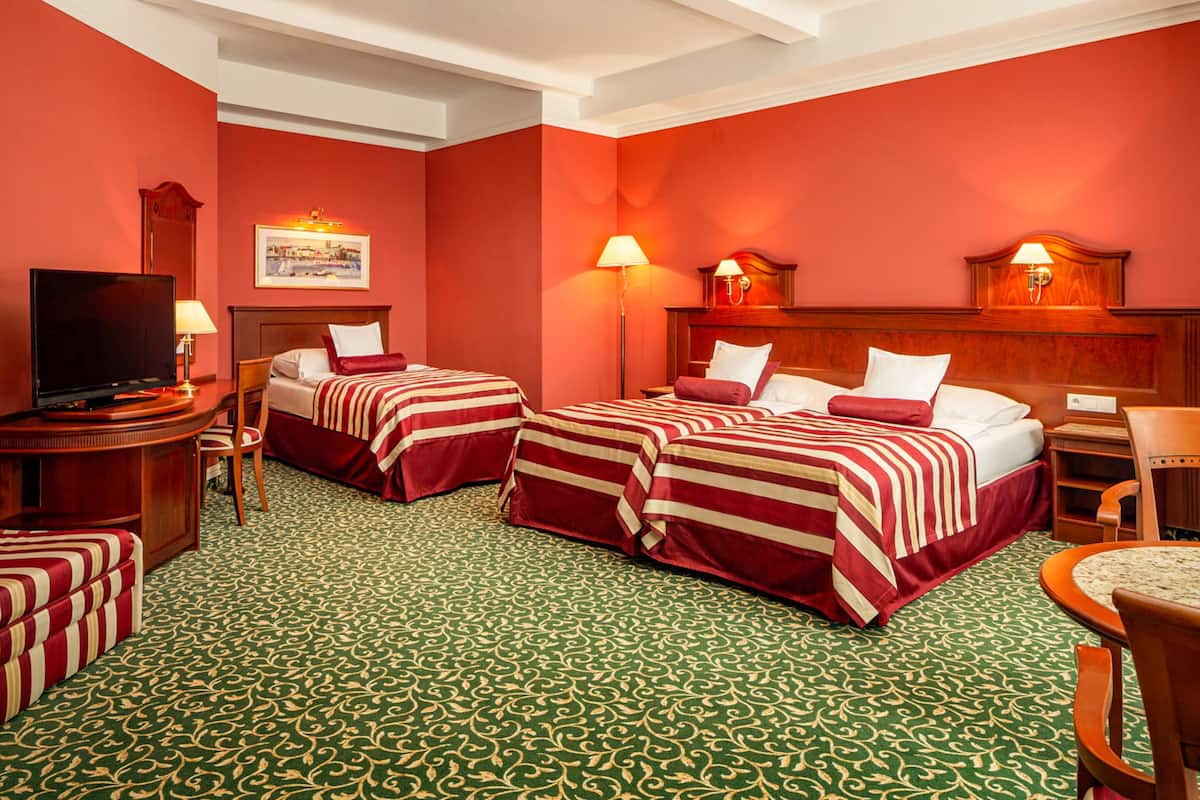 Quarto de hotel com duas camas, televisão, escrivaninha e cadeira.