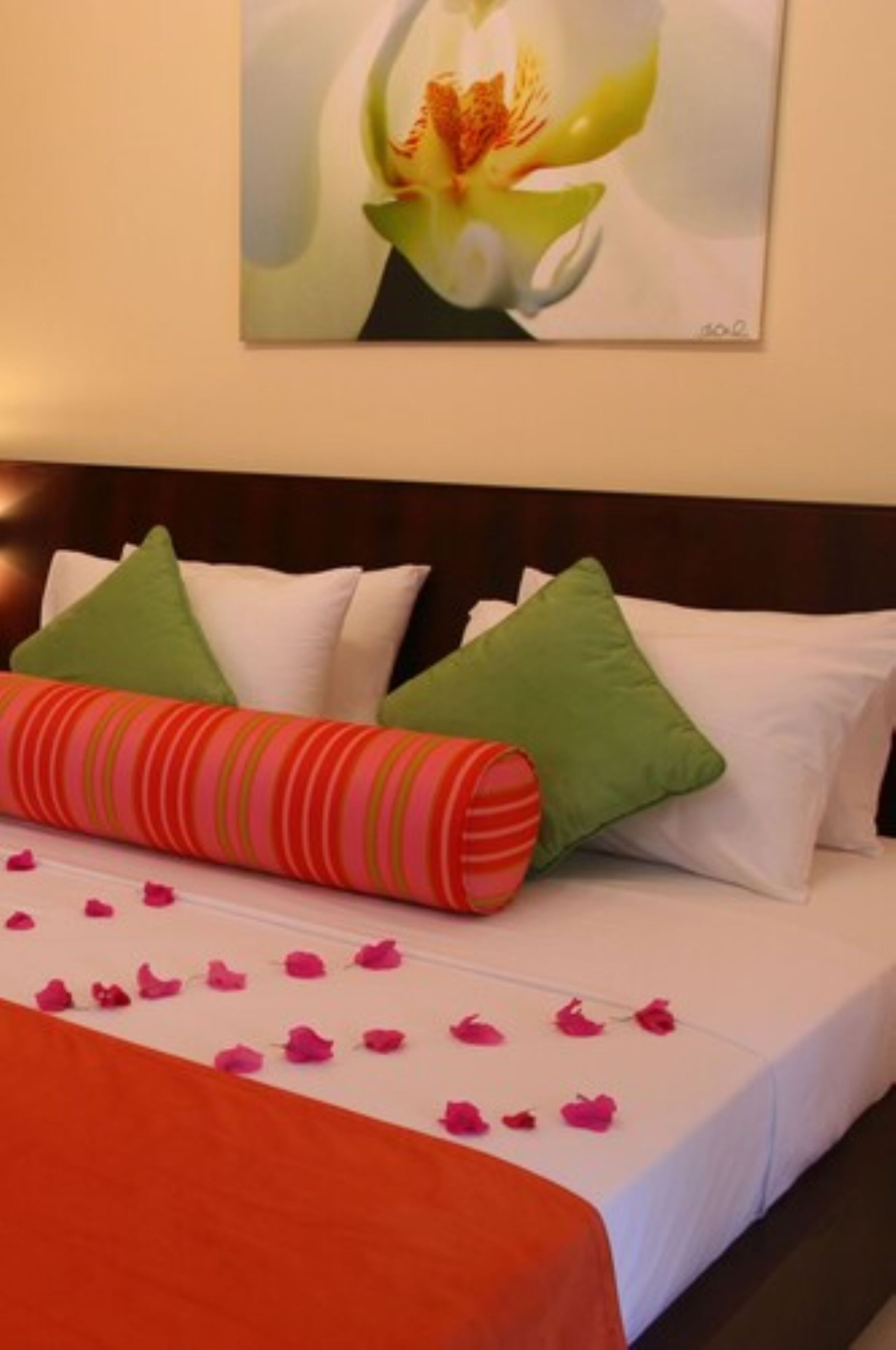 Quarto de hotel com cama, almofadas e uma obra de arte na parede.