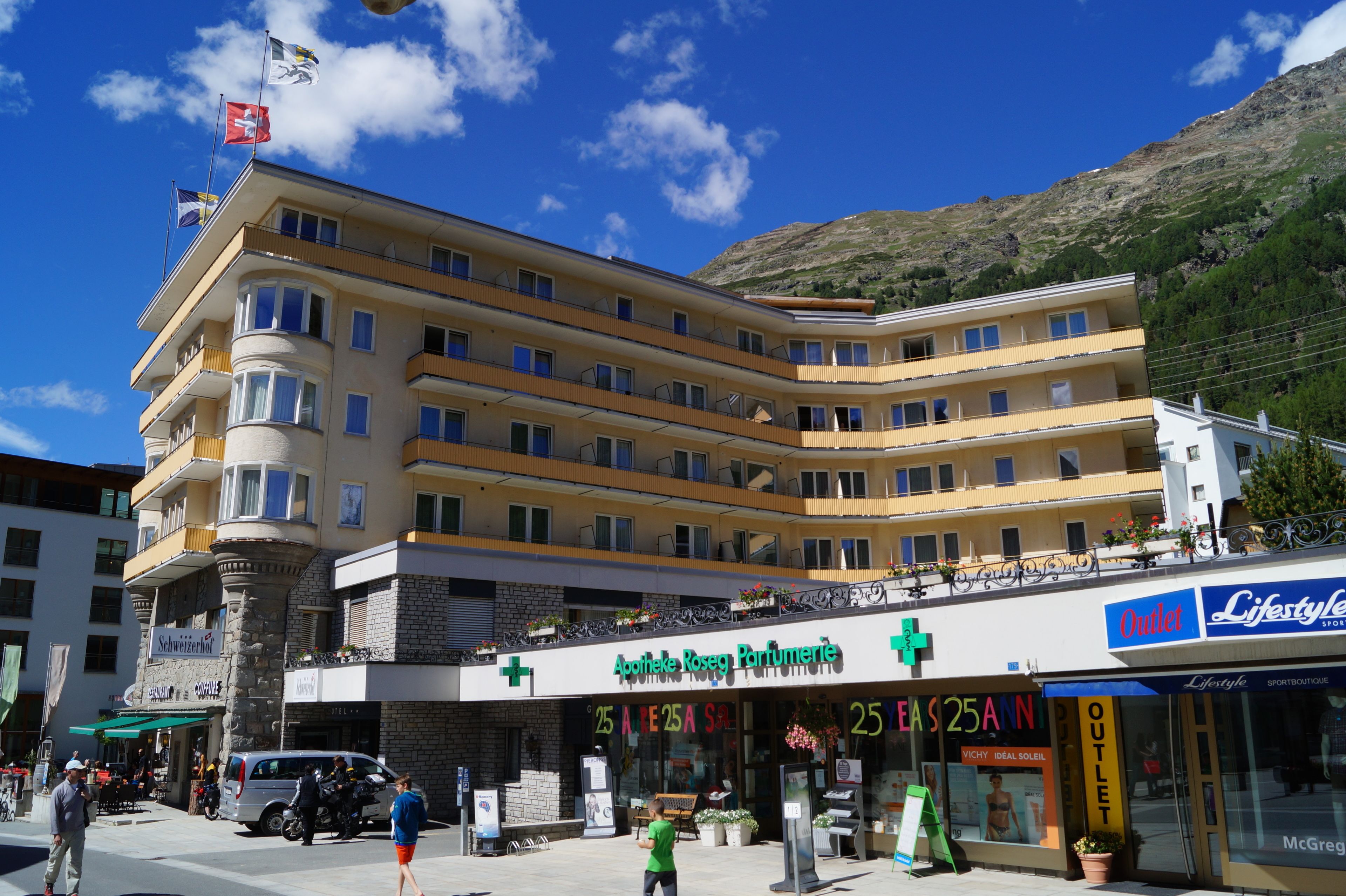 Um hotel com vários andares, varandas, uma farmácia e uma loja de descontos.