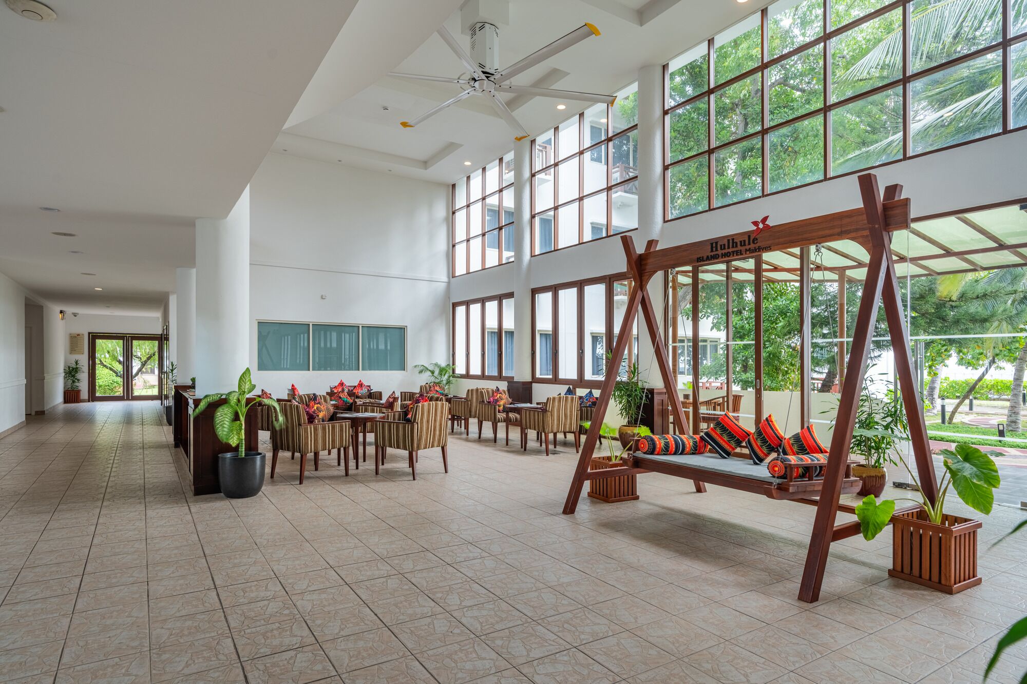 Espaçoso espaço interno com área de estar ampla, com balanço, várias mesas e cadeiras.