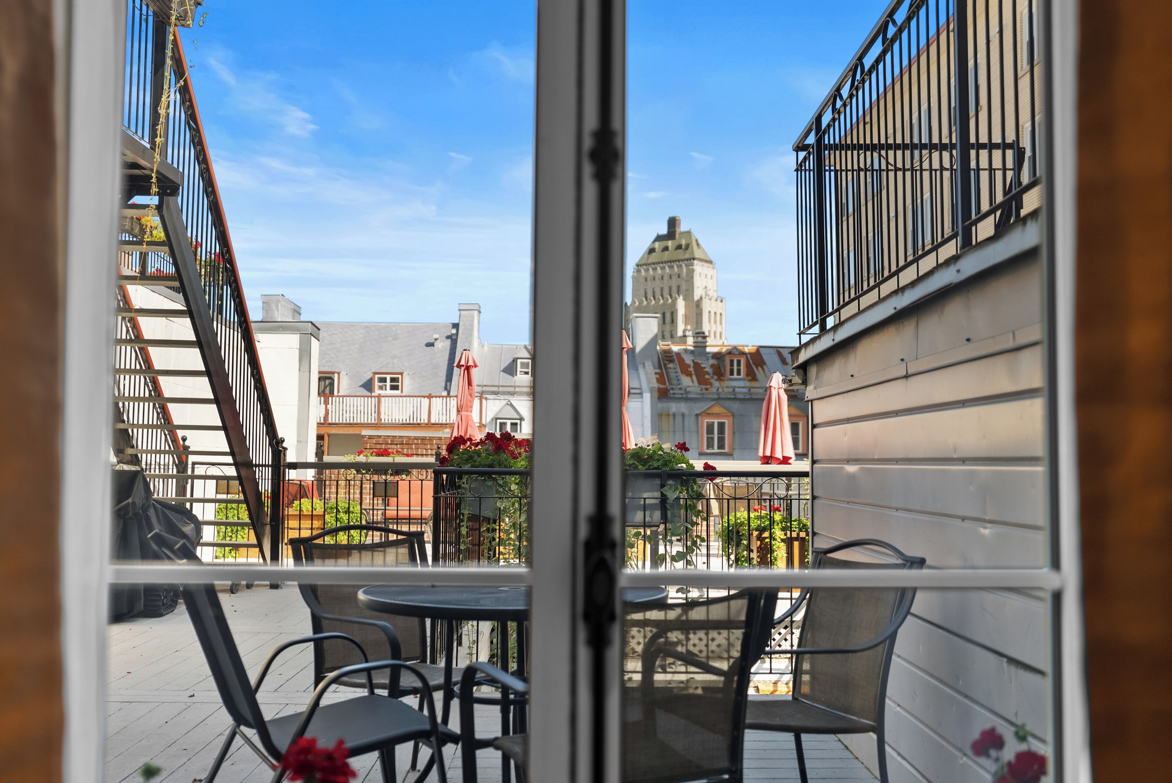 Varanda com mobiliário de exterior, vista para edifícios e céu claro.