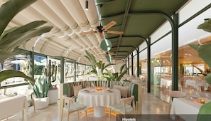Um restaurante com mesas redondas, cadeiras, plantas em vasos e um ventilador de teto.
