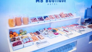 Buffet com diversos alimentos e uma placa para o MB Boutique Hotel.