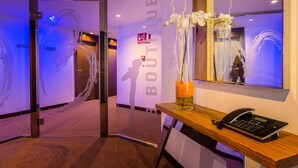 Um interior moderno com uma mesa de recepção, um telefone e uma parede com a inscrição 'BOUTIQUE'.