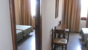 Um quarto com uma cama, uma mesa e uma cadeira.
