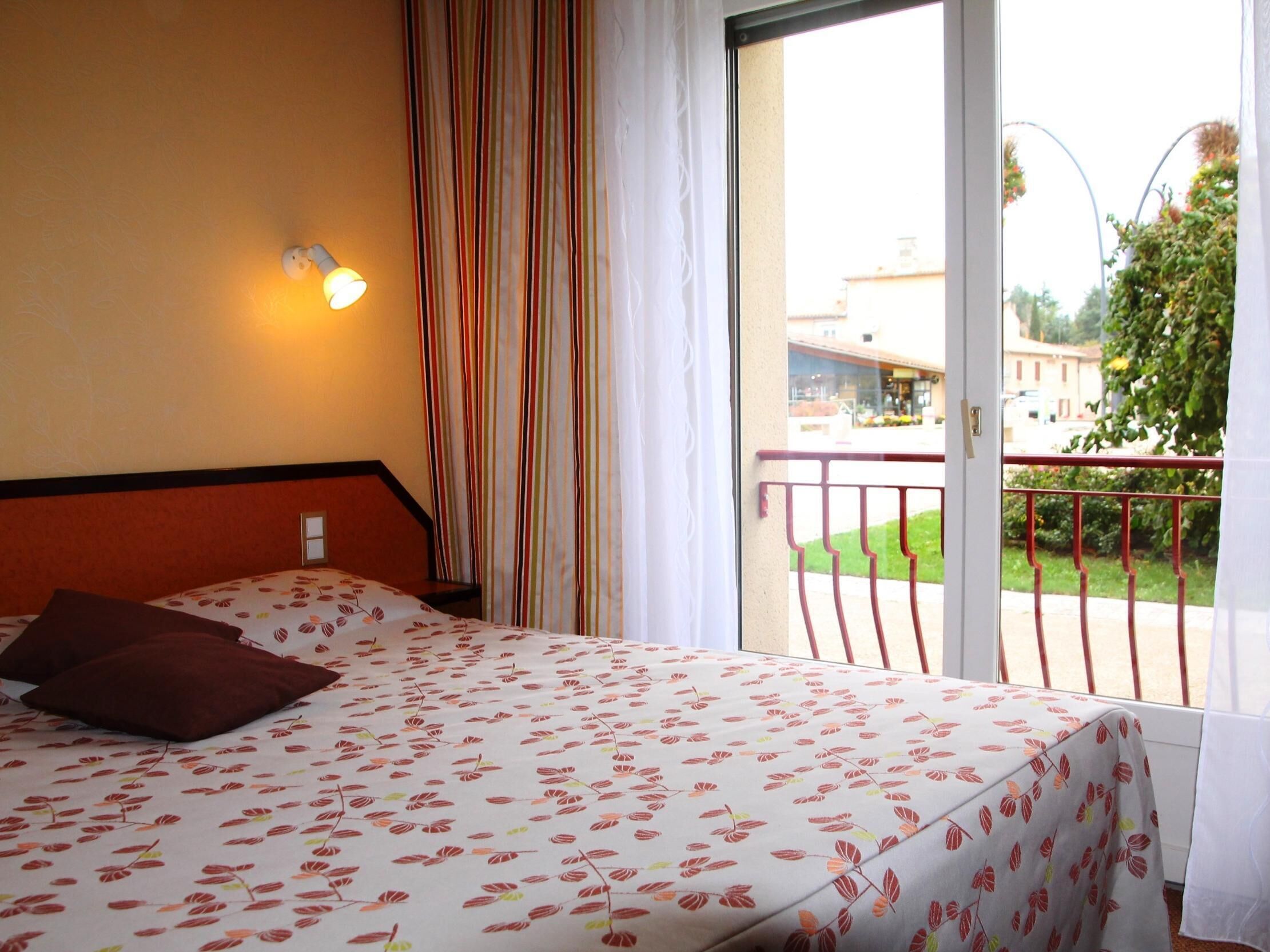 Quarto de hotel com cama, janela com cortinas e vista para o exterior.