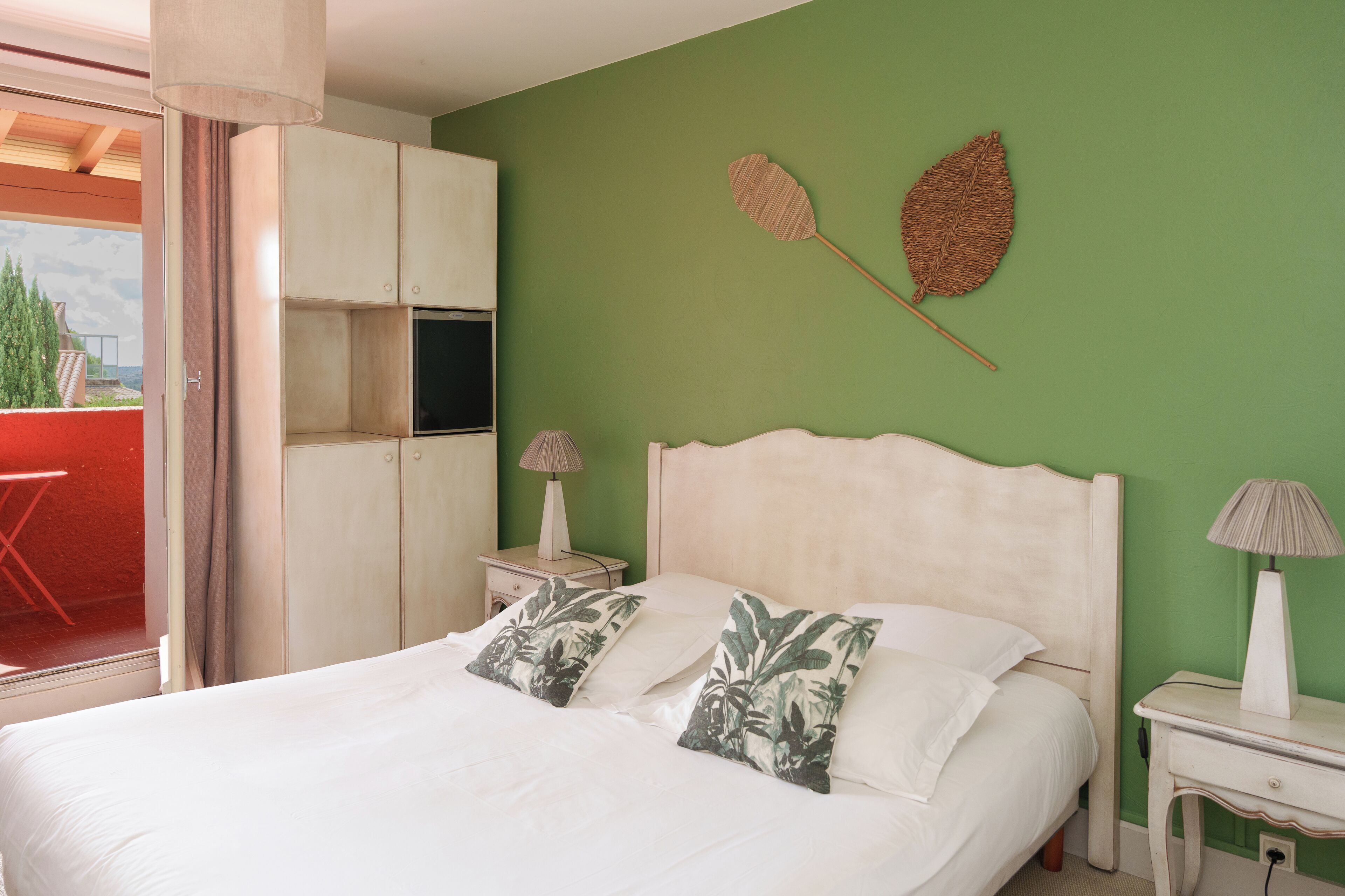 Quarto com uma cama, duas mesas de cabeceira, um guarda-roupa e vista para o exterior.