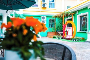 Uma área de estar ao ar livre vibrante, com parede verde, escultura de estrela vermelha e plantas em vasos.