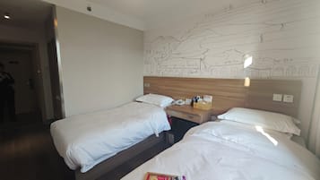 Quarto de hotel com duas camas, cabeceira de madeira, mesa de cabeceira com telefone e artigos de higiene pessoal, e um mural na parede.